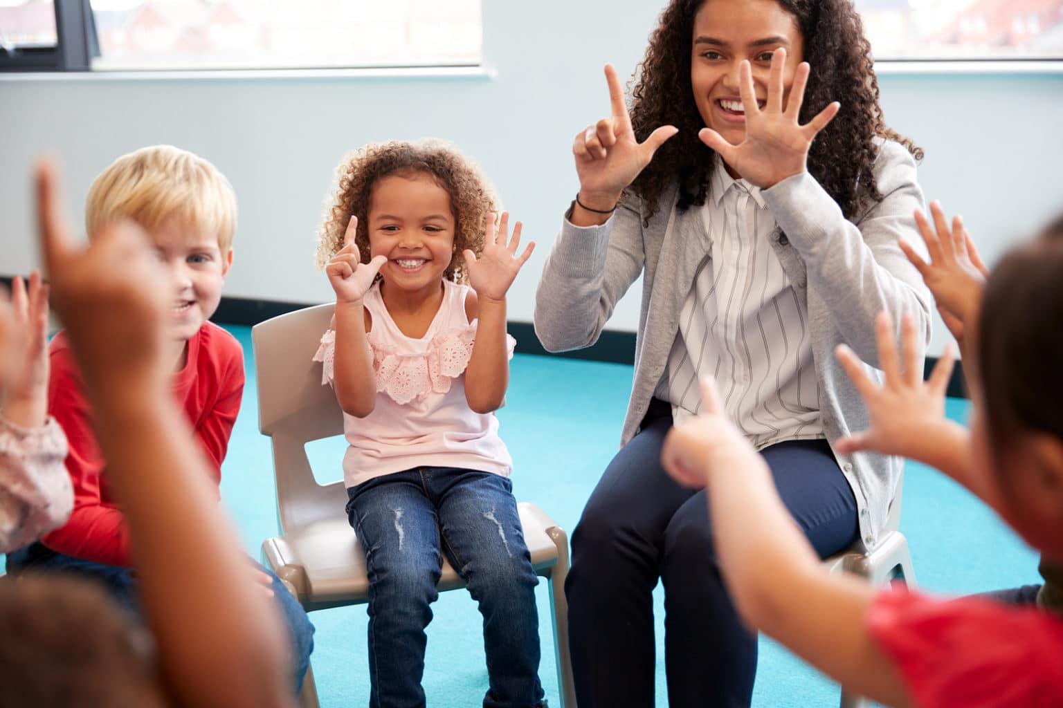 Front view of infant school children sitting on chairs in a circ ...
